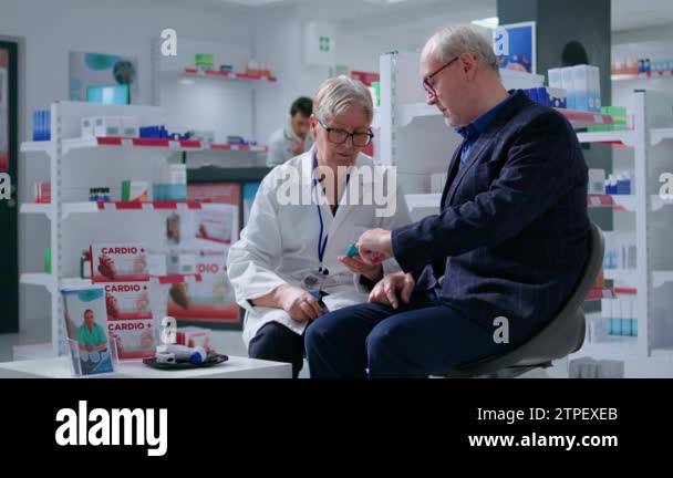 Elderly pharmacist in drugstore using medical device to check senior ...