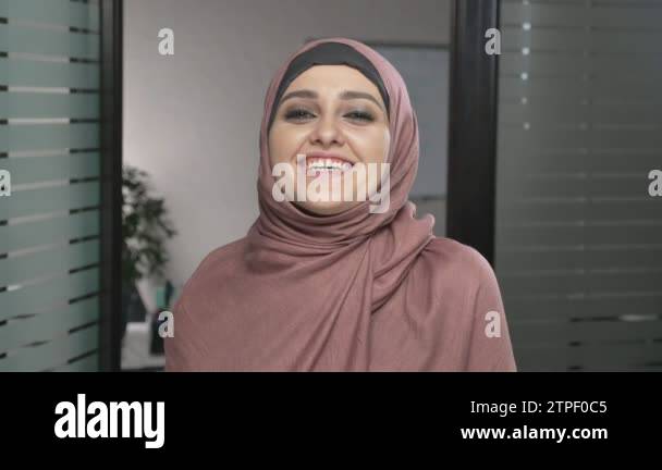 Young happy Arab girl in pink hijab laughs. Looks at the camera ...