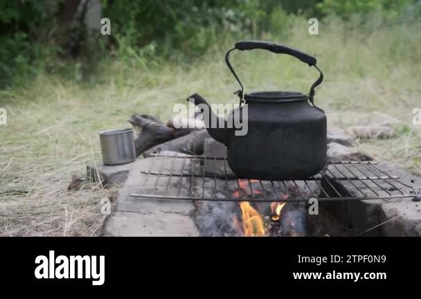 Old kettle standing on a tourist campfire in nature. Blackened with ...