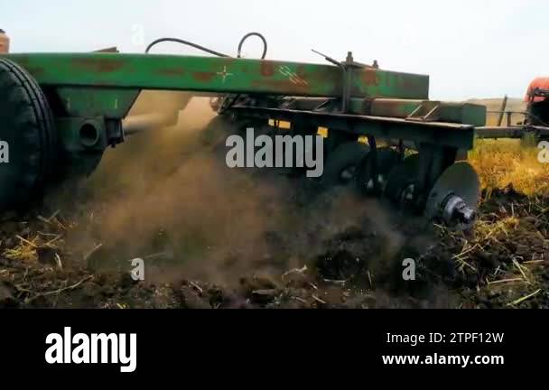 The mechanical plow moves behind the tractor and plows the earth Stock ...