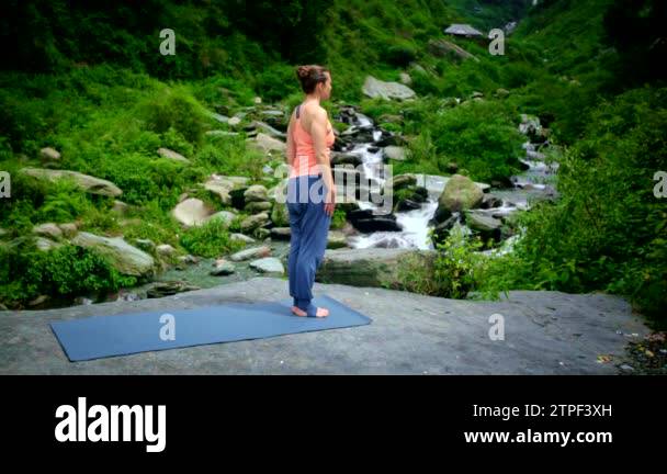 Woman doing yoga Sun Salutation Surya Namaskar asana sequence outdoors ...
