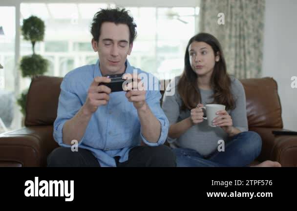 4K Competitive man playing video games at home, with bored pregnant ...