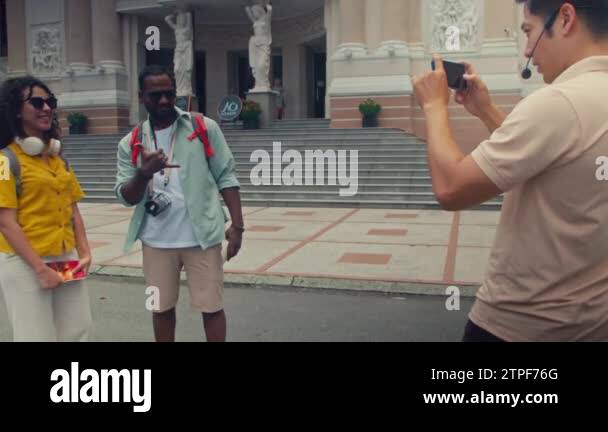 Medium shot of Asian male tourist guide taking photo of multiethnic ...