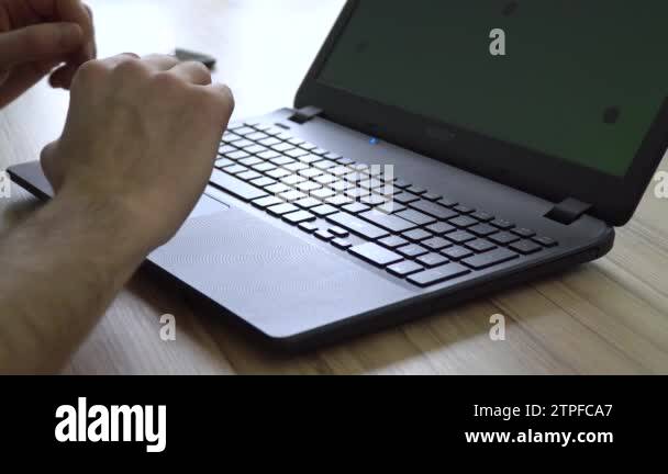 Man typing on laptop keyboard, a green screen. The camera shoots from ...
