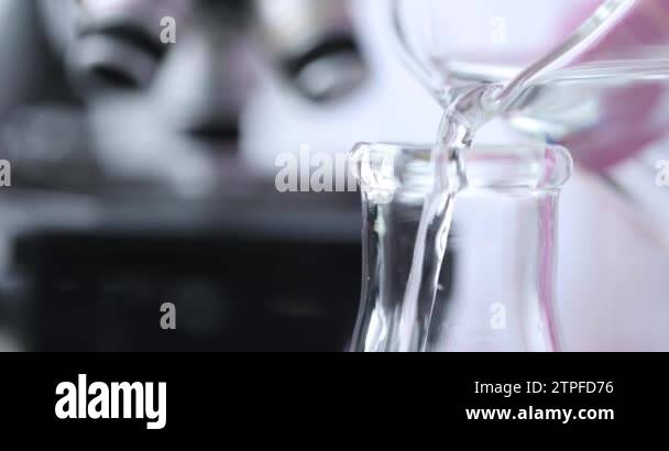 Scientist chemist pouring water from test tube into flask in laboratory ...