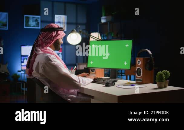 Arabic man looking at mockup computer screen while working from home ...
