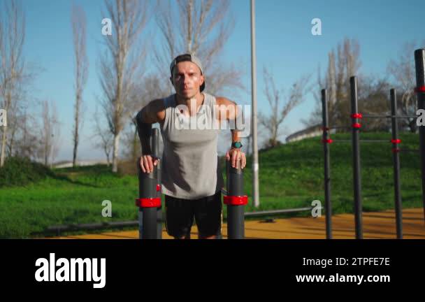 Man using parallel bars for triceps workout in outdoor setting. Athlete ...