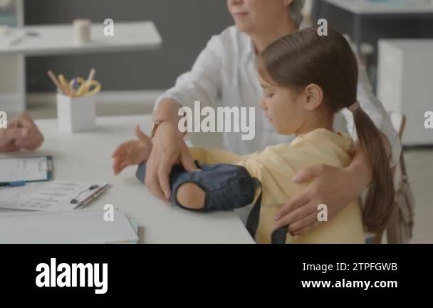 Waist up of caring mother taking off arm sling from her little ...