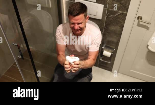 Man sits on toilet with toilet paper and suffers from constipation ...