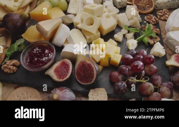 Variety of sliced cheeses with fruits, mint, nuts and cheese cutting ...
