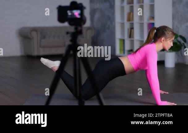 Female athletic fitness instructor doing exercises live on camera for ...