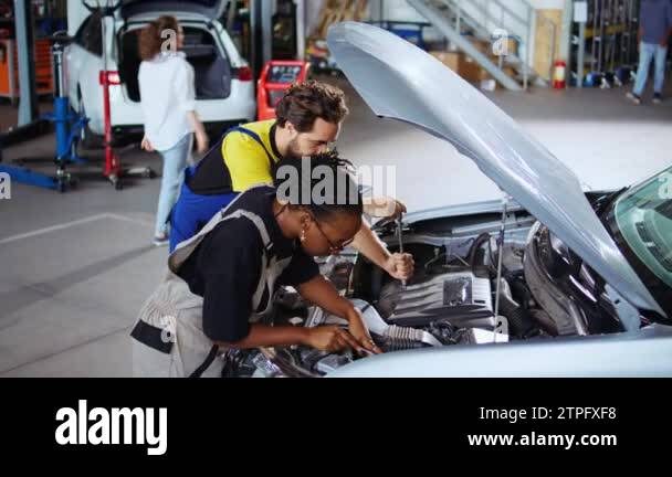 Repair shop workers using torque wrench and screwdriver to fix car in ...