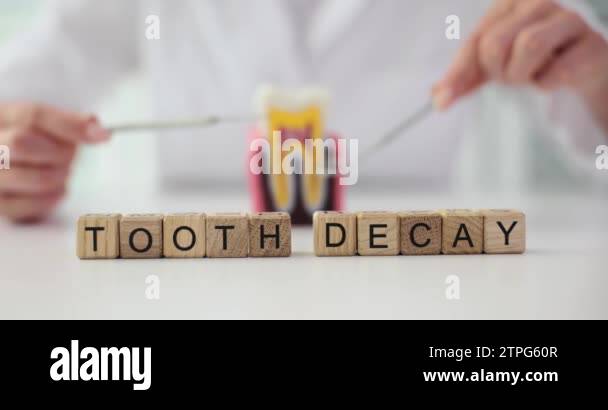 Dentist shows artificial tooth and dental instruments word tooth decay ...