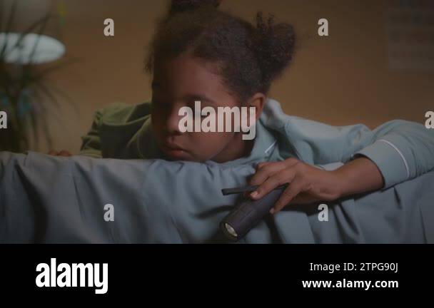 Slowmo of scared African American little girl with flashlight looking ...