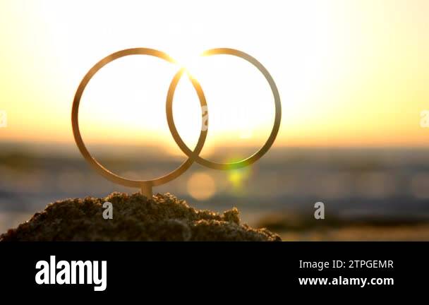 Black outlines of wedding rings at dawn and sunset on seashore. Stick ...