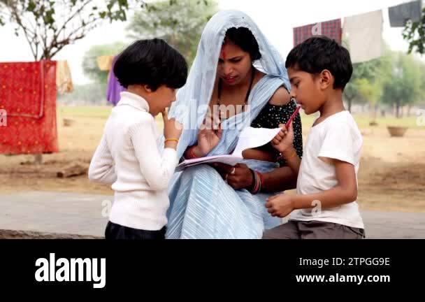 Indian village woman in saree teaching little daughter and son to read ...