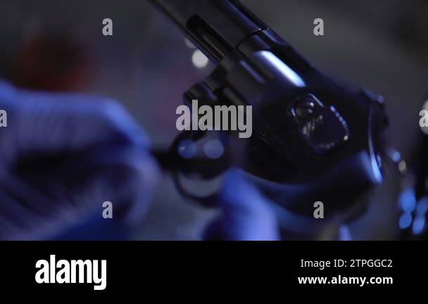 Forensic expert watching serial number on revolver, using magnifying ...