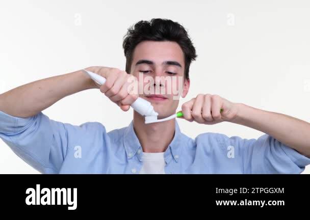 Happy Caucasian man smiles brightly as he applies toothpaste onto his ...