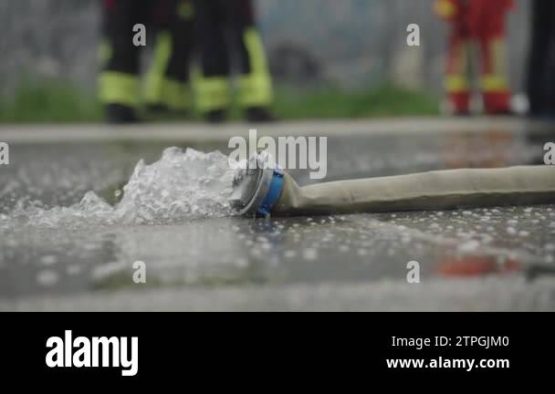 An up-close shot captures a fire hose with a powerful stream of water ...