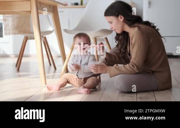 Nurturing mother tenderly feeds little son. Eyes are filled with ...