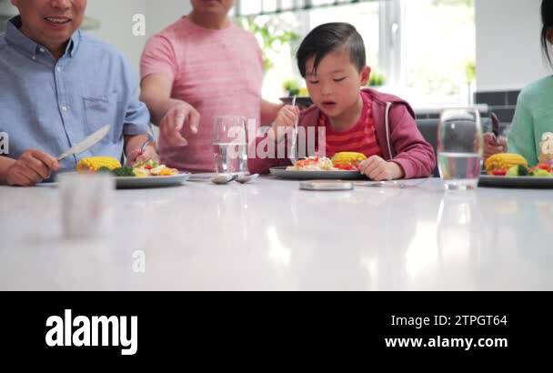 Little boy is enjoying a stir fry dinner while with his family at home ...