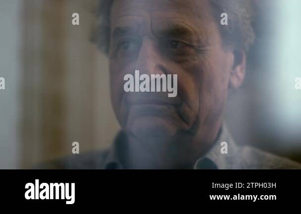One serious older man seen thinking about life, seen through window ...