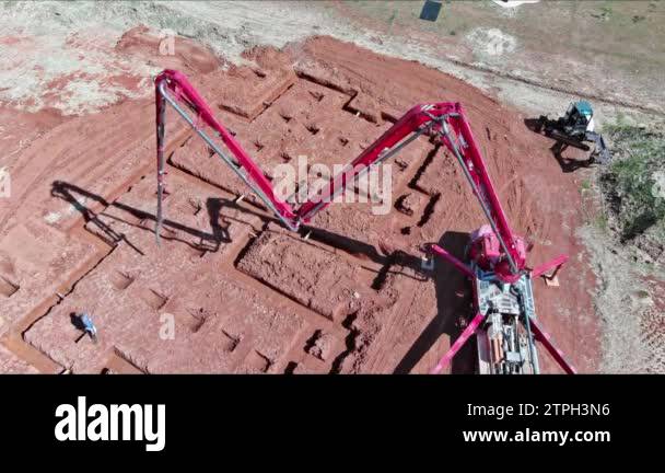 Concrete is poured for laying foundation of building by worker using an ...
