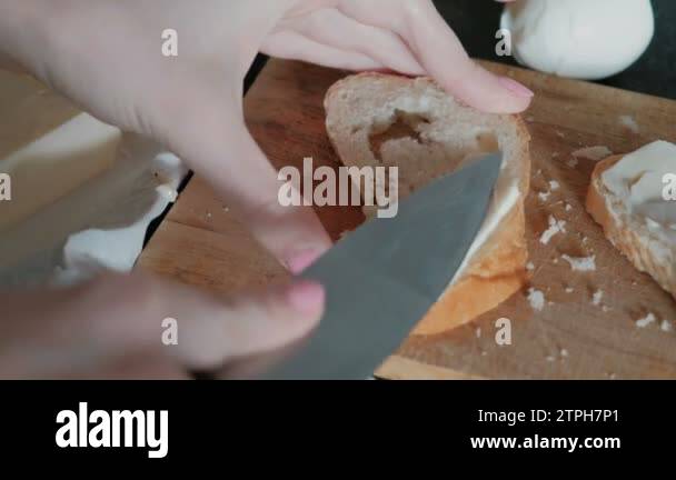 Close-up of the womans hands smear butter on a piece of bread, using a ...