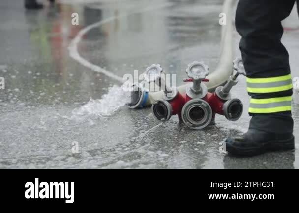 An up-close shot captures a fire hose with a powerful stream of water ...