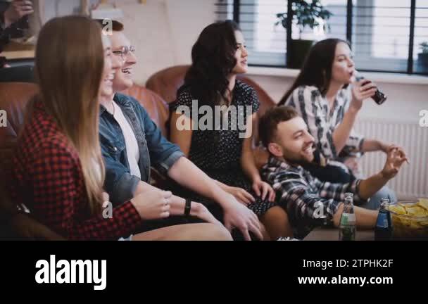 Friends sit on couch, watch funny film on TV. Caucasian young group sit ...