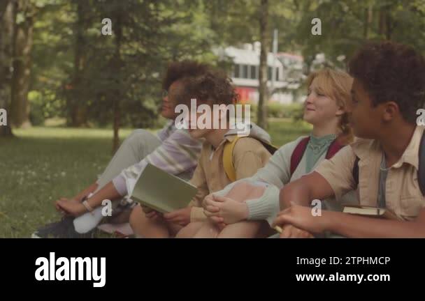 Small group of diverse preteen schoolkids raising their hands while ...