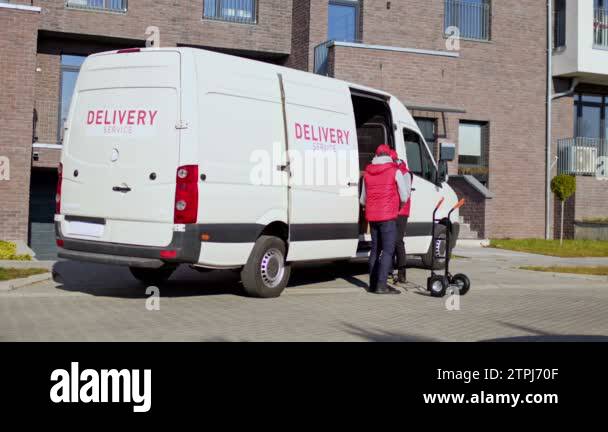 Couriers putting parcel box on the trolley from van to deliver them to ...
