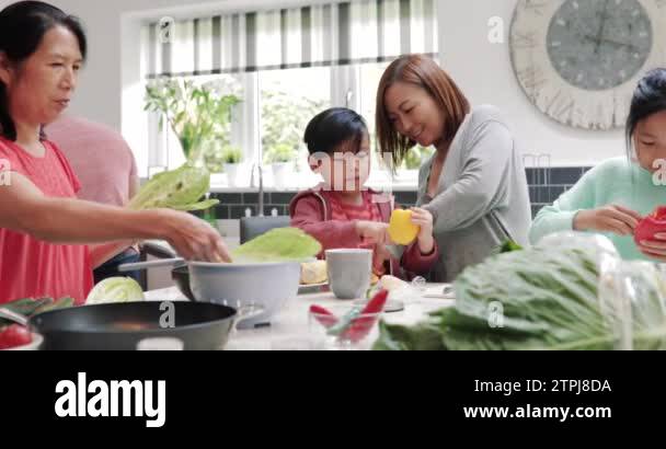 Three generation family are all helping to make a stir fry together at ...