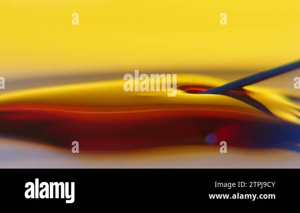 Metallic needle pierces the red liquid surface in the yellow background ...