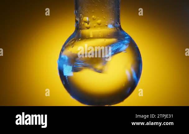 Transparent water with blue tints is shaken in a round bottom flask in ...