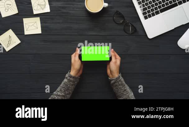 Top view on the black office desk and black smartphone with green ...