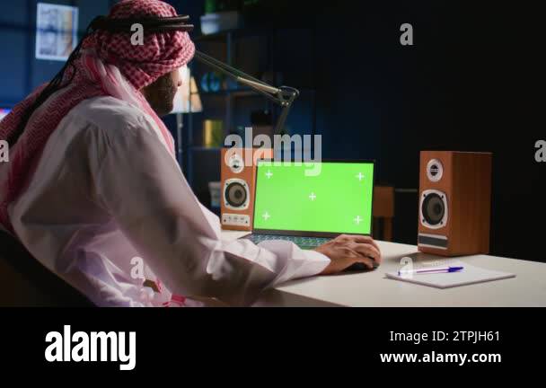 Muslim man scrolling on green screen laptop, checking social media feed ...