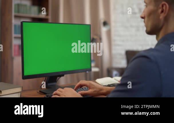 Young Man Sits at Desk in Office and Works at Desktop Computer with ...
