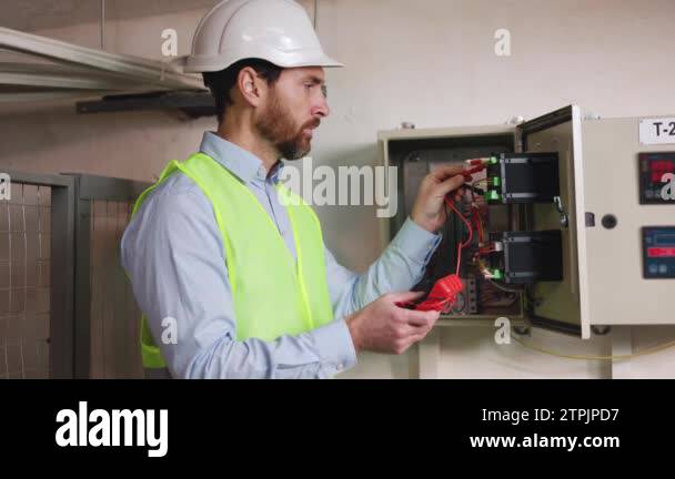 Focused electrician uses electrical tester to check the functionality ...
