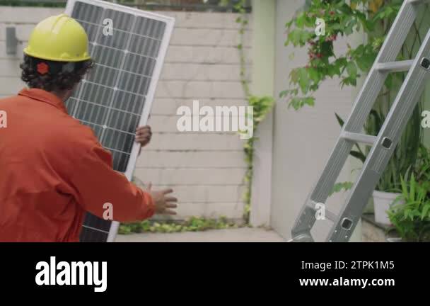 Two multi-ethnic male workers installing PV system on rooftop of house ...