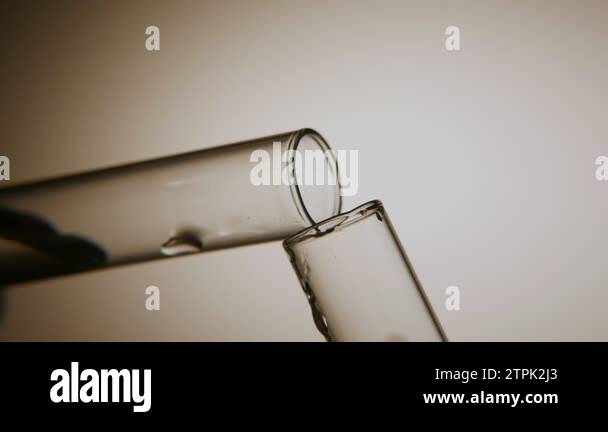 Clean water is poured from one sample tube into another in a chemical ...