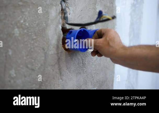 Installation of socket boxes in a brick wall. Male worker installing a ...