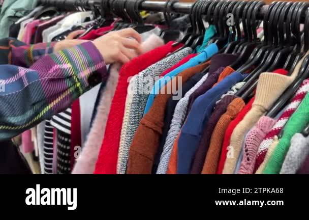 A young woman chooses clothes in a second-hand shop. Thrift store ...