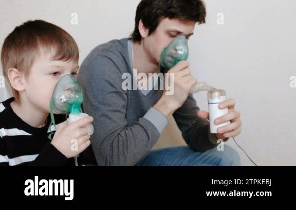 Use nebulizer and inhaler for the treatment. Man and boy inhaling ...