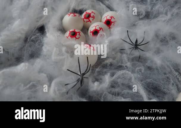 Six gouged out human eyeballs lie in a thick web. A strong wind blows ...