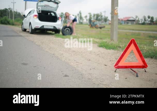 Girl changing a punctured tire at the car. repair of cars on the road ...