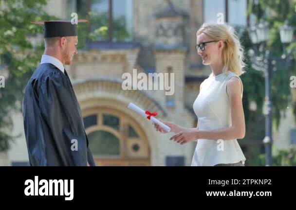 Teacher Gives a Diploma to Graduand Young Man Smiling Shows the Diploma ...