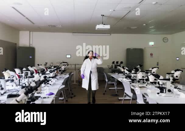 Female research scientist looking at samples under microscope. 4K ...