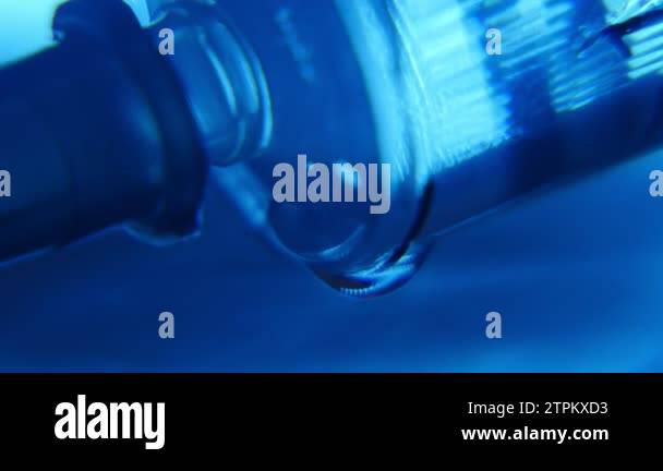 Dazzling water is pulled out from a plastic syringe in blue medical ...