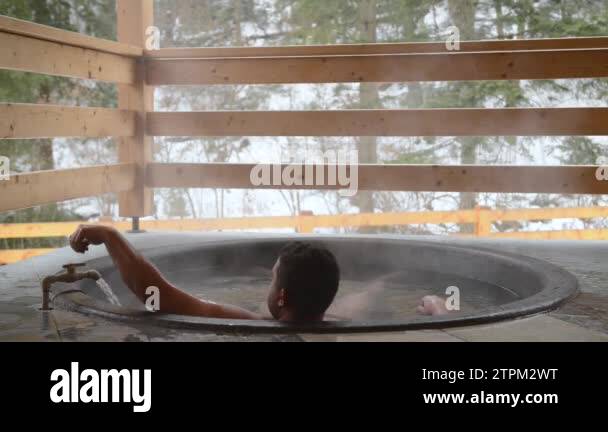 A man is bathing in the cast iron vat with mineral water and turned off ...